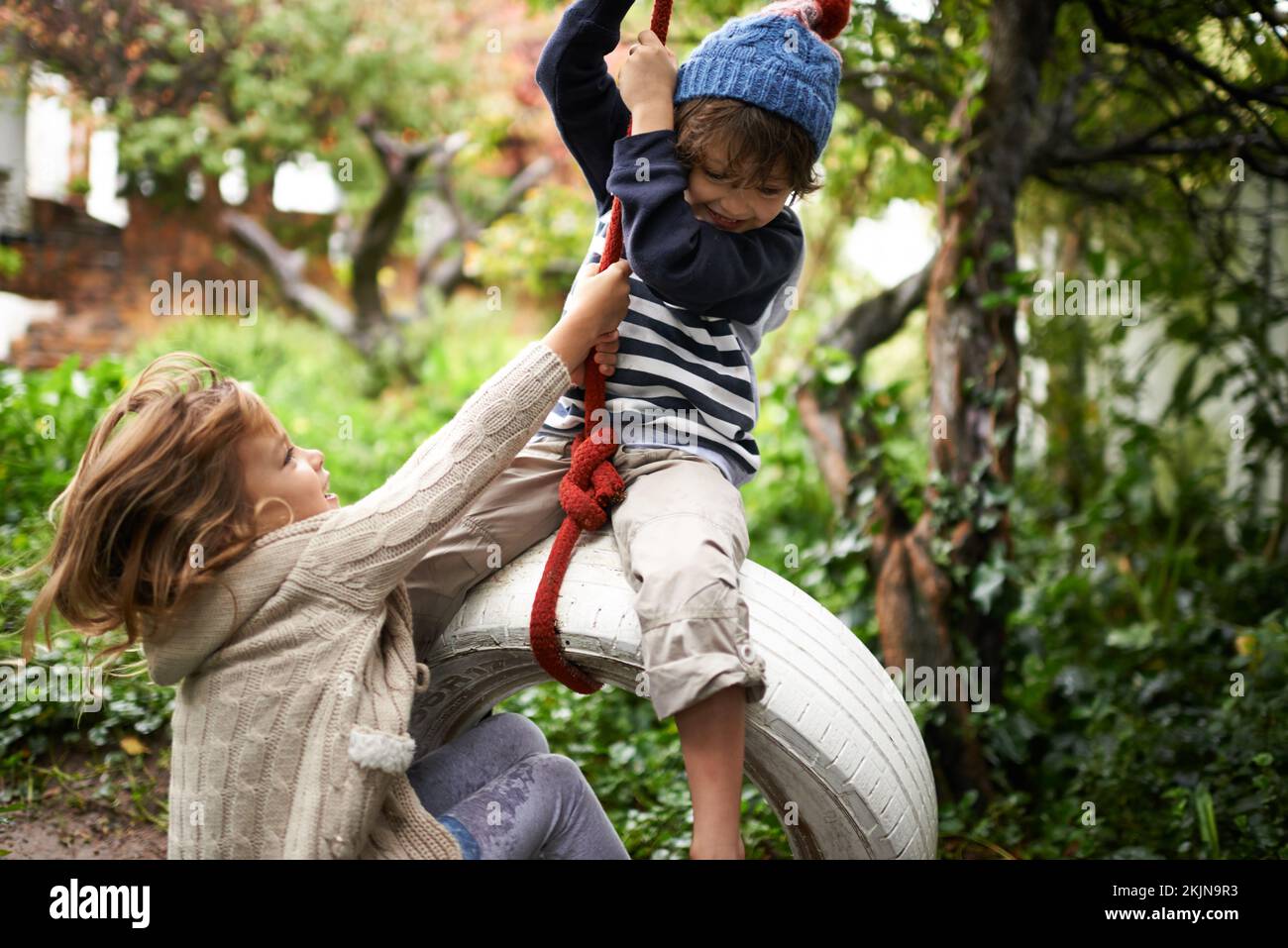 Tarzan and Jane. two cute kids playing on a tire swing in their garden ...