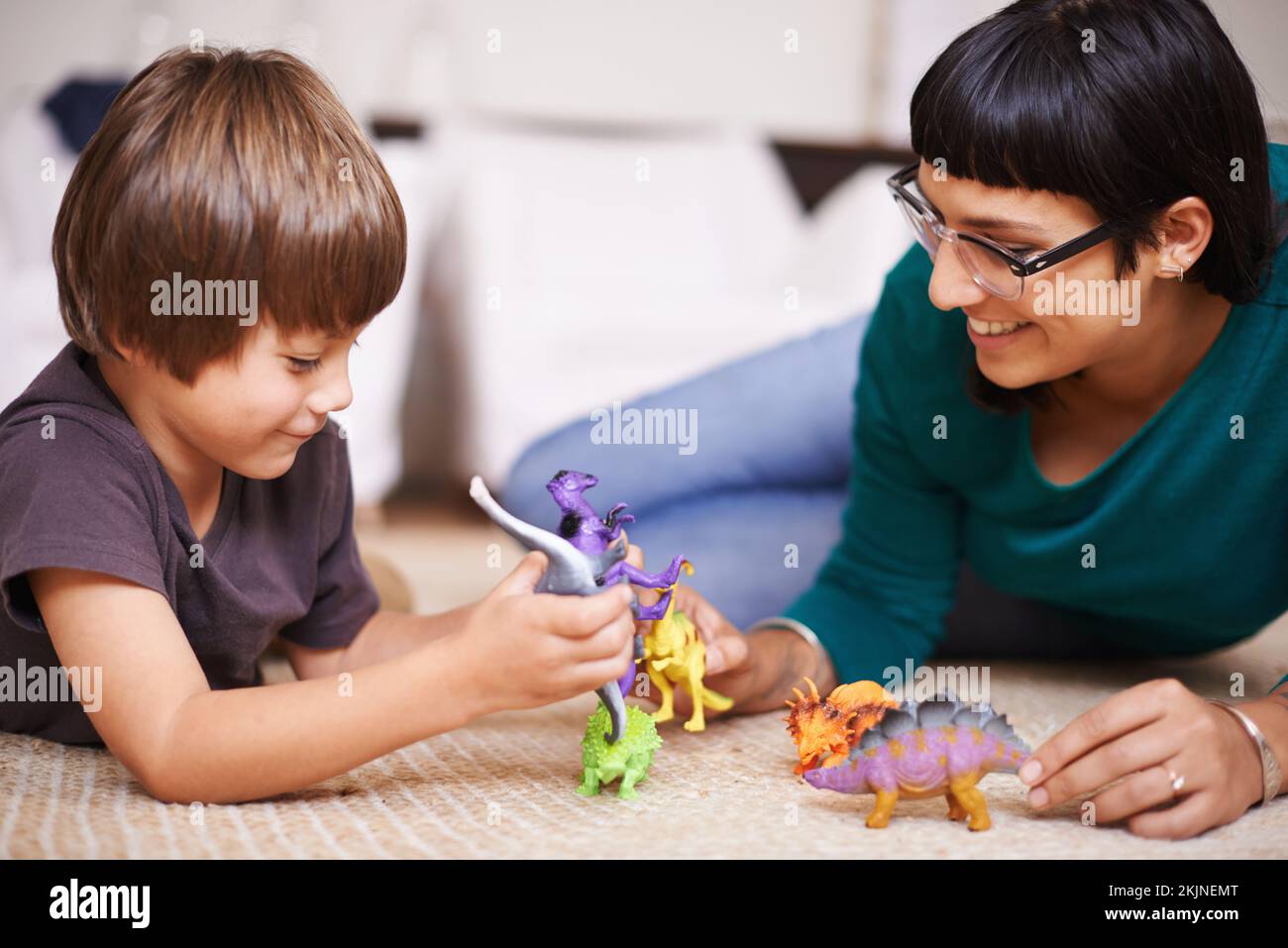 Having some fun with dinosaurs. a mother and her son playing with toy ...