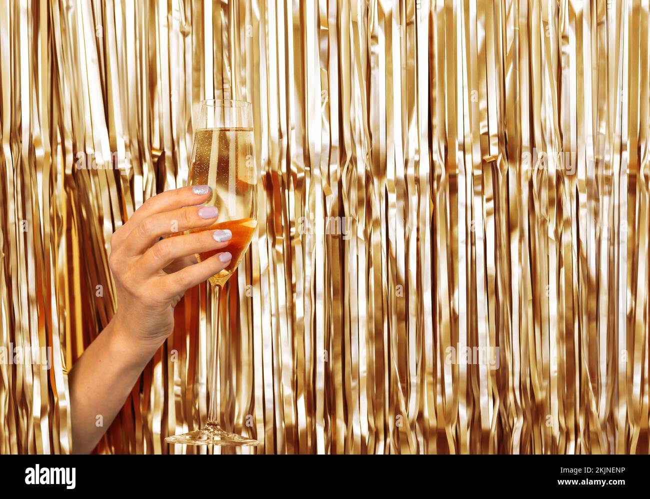 Woman hand holding glass of champagne on metallic golden background ...