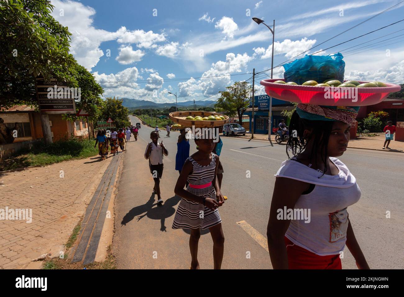 Street vendor girls walking on a street with fruit baskets on their ...