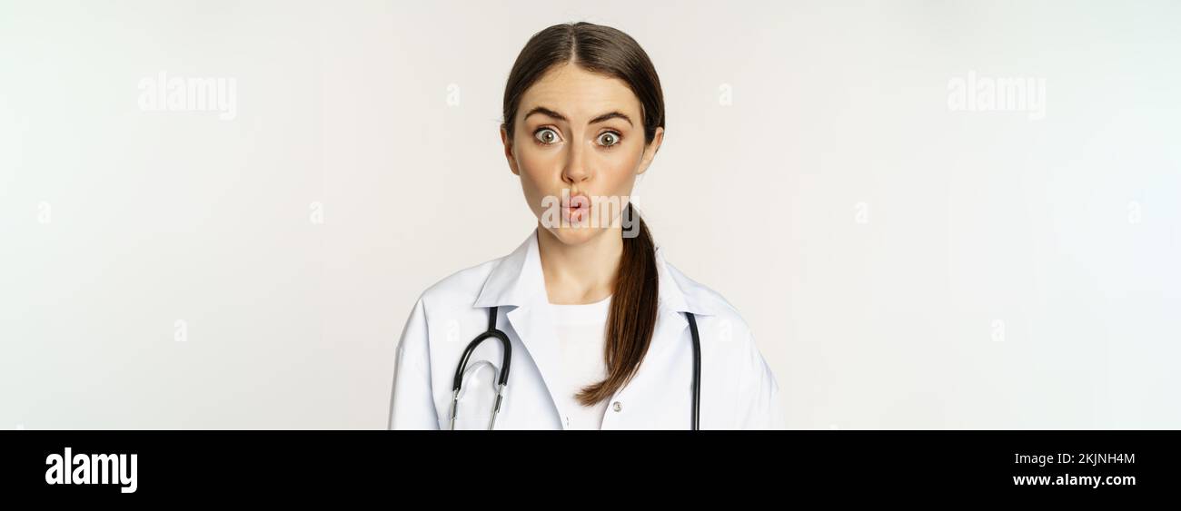 Portrait of woman doctor looking surprised, amazed, reaction of ...