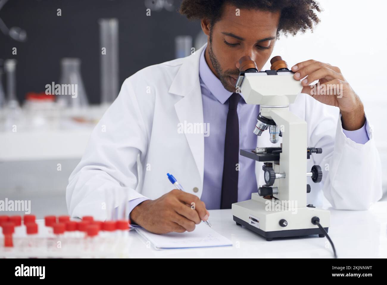 Zooming in on a virus. a male biologist looking at a glass slide ...