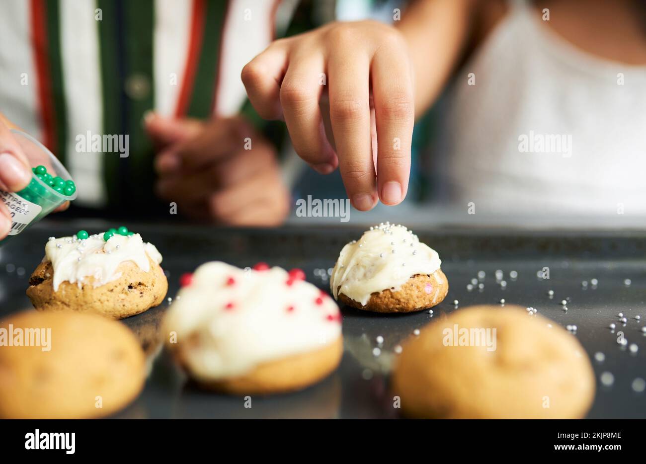 Girl hands, decorating cookies and closeup with sparkles, cream or ...