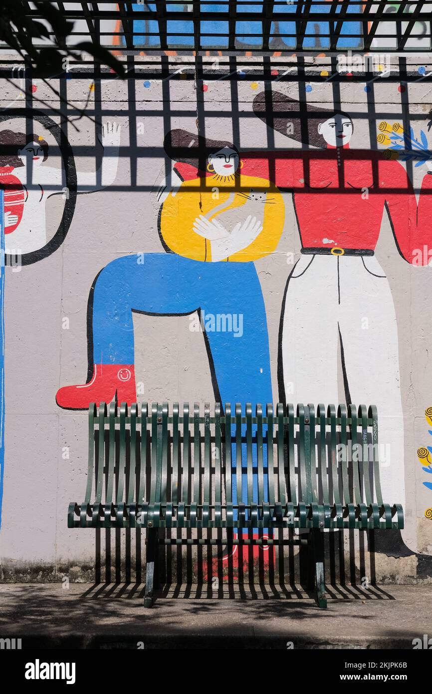 A vertical view of a bench with street art on the wall behind in Coulee ...