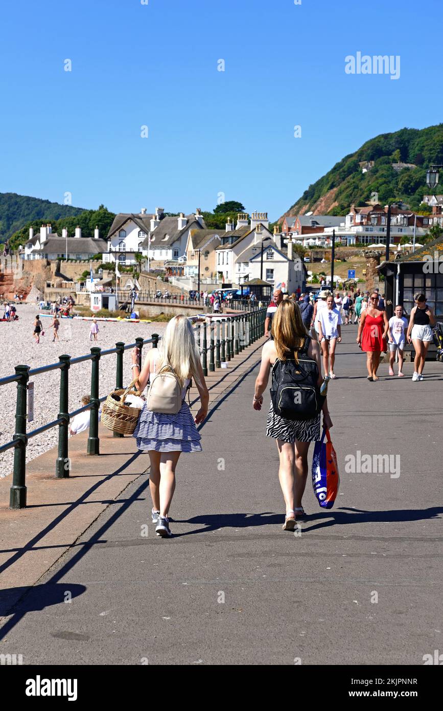 Tourists walking along the promenade with the beach to the left ...