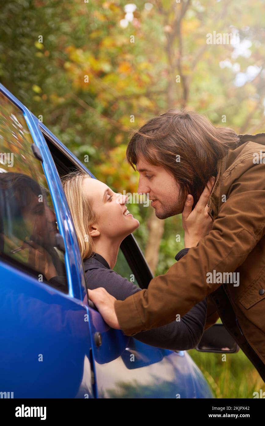 Lingering goodbyes. a young couple kissing each other goodbye through a ...