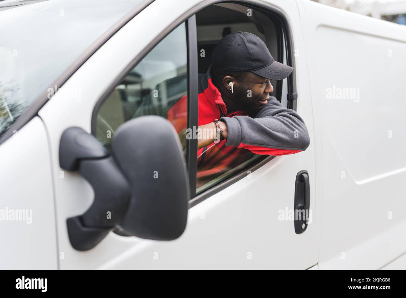 Young adult black delivery guy wearing work unifrom driving white van ...