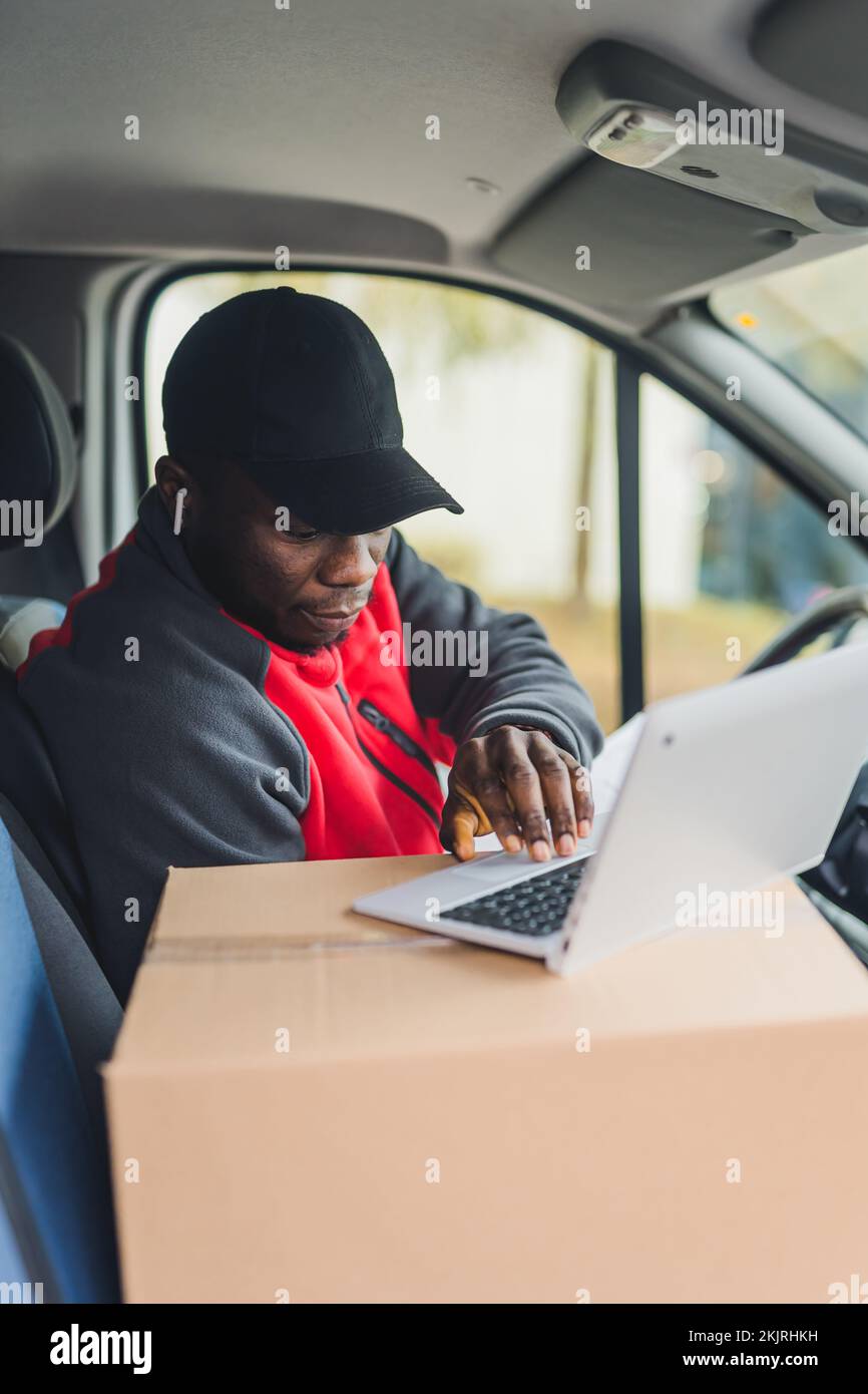 Young adult black delivery guy wearing work uniform sitting in driver ...