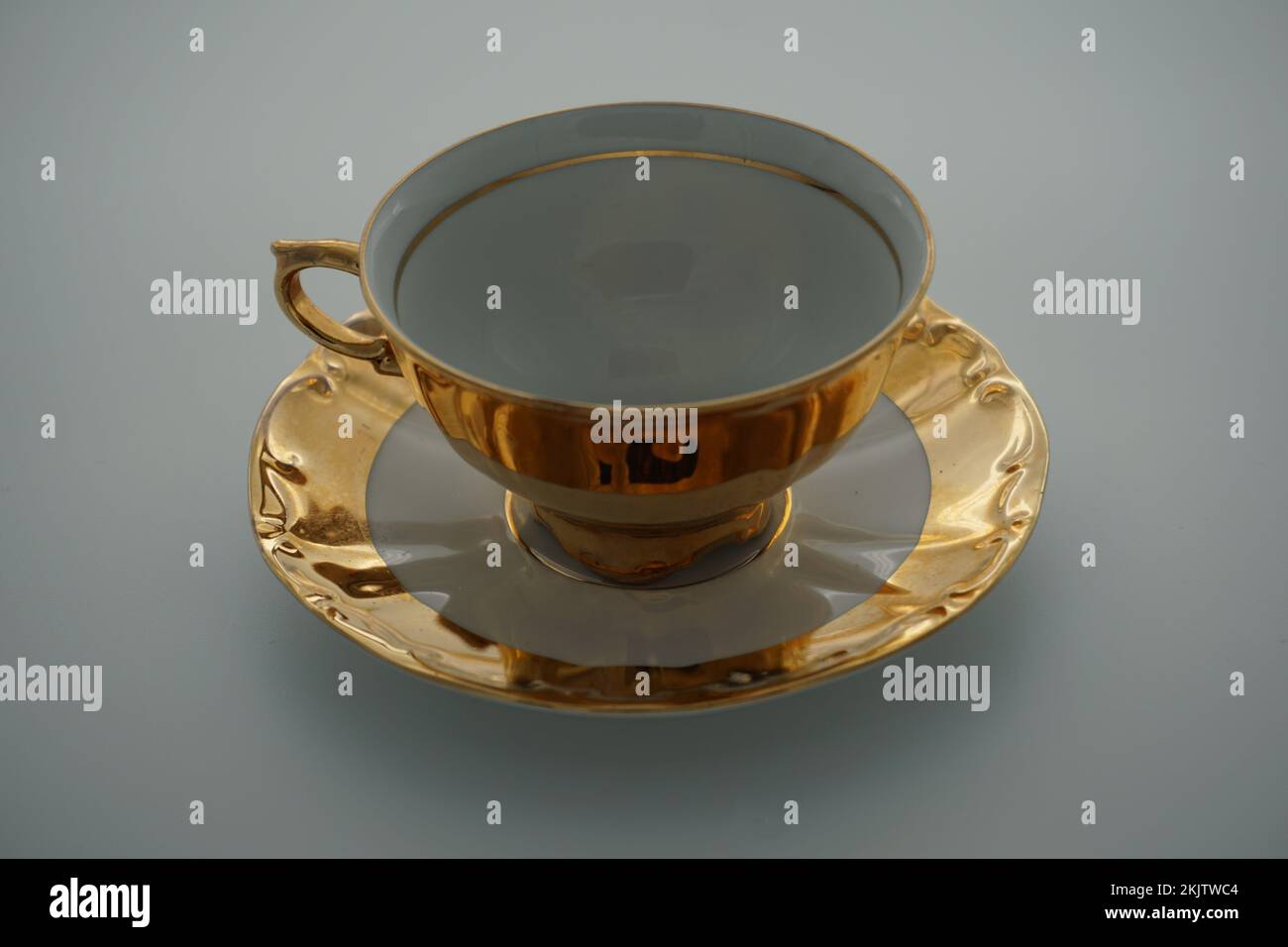An old-fashioned golden porcelain teacup and saucer isolated on a white ...
