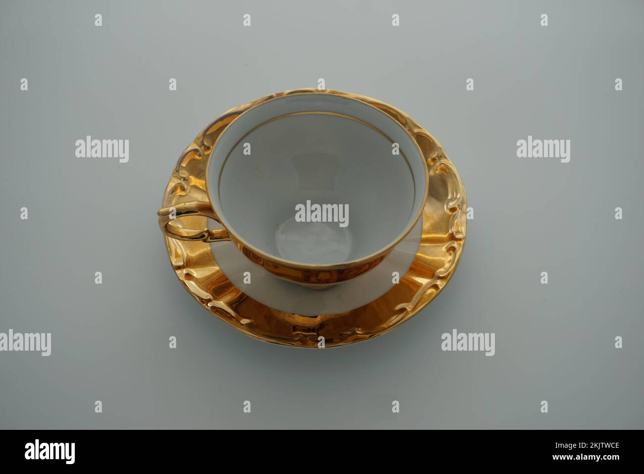 An old-fashioned golden porcelain teacup and saucer isolated on a white ...