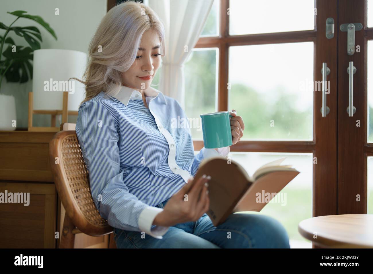 Portrait of an Asian business woman drinking coffee while reading book ...