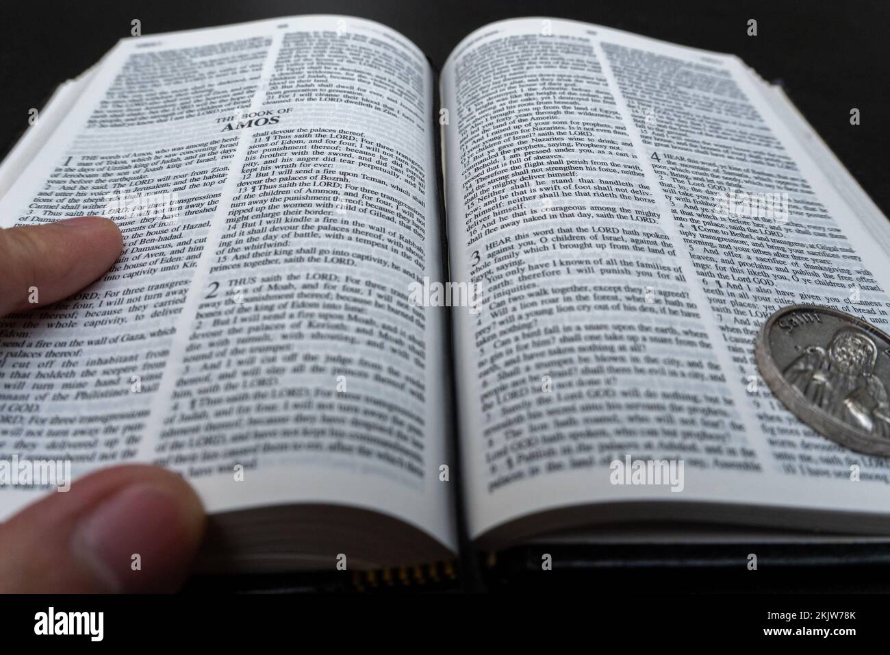 A closeup of an open Bible on a dark background with a silver prayer ...