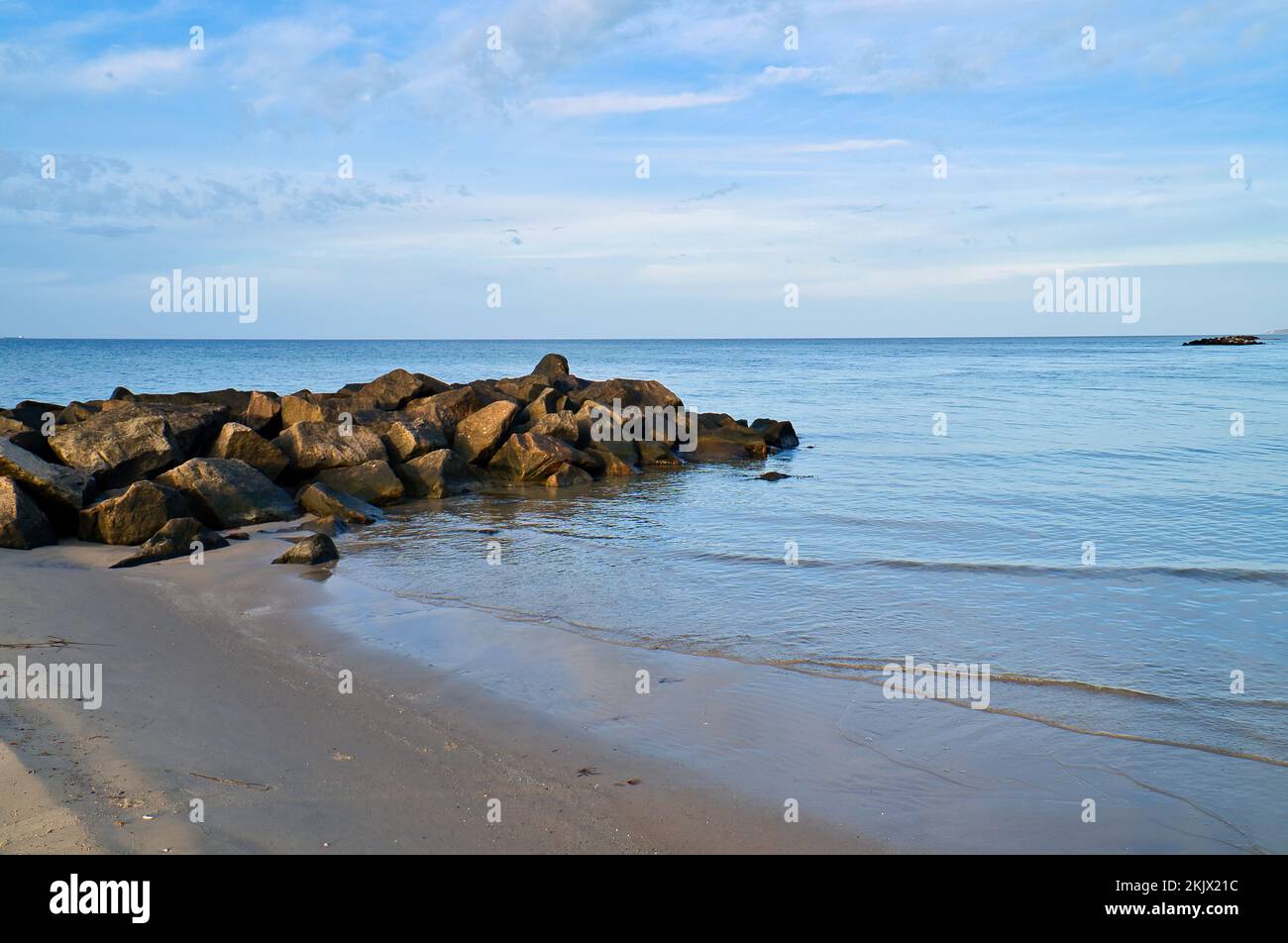 Stone groyne jutting into sea in Denmark with clouds in sky. Coastal ...