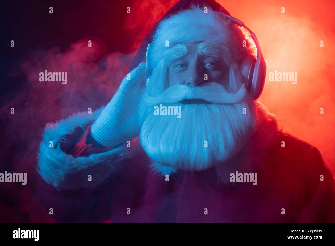 Santa claus listens to music with headphones at a party. Blue red neon ...