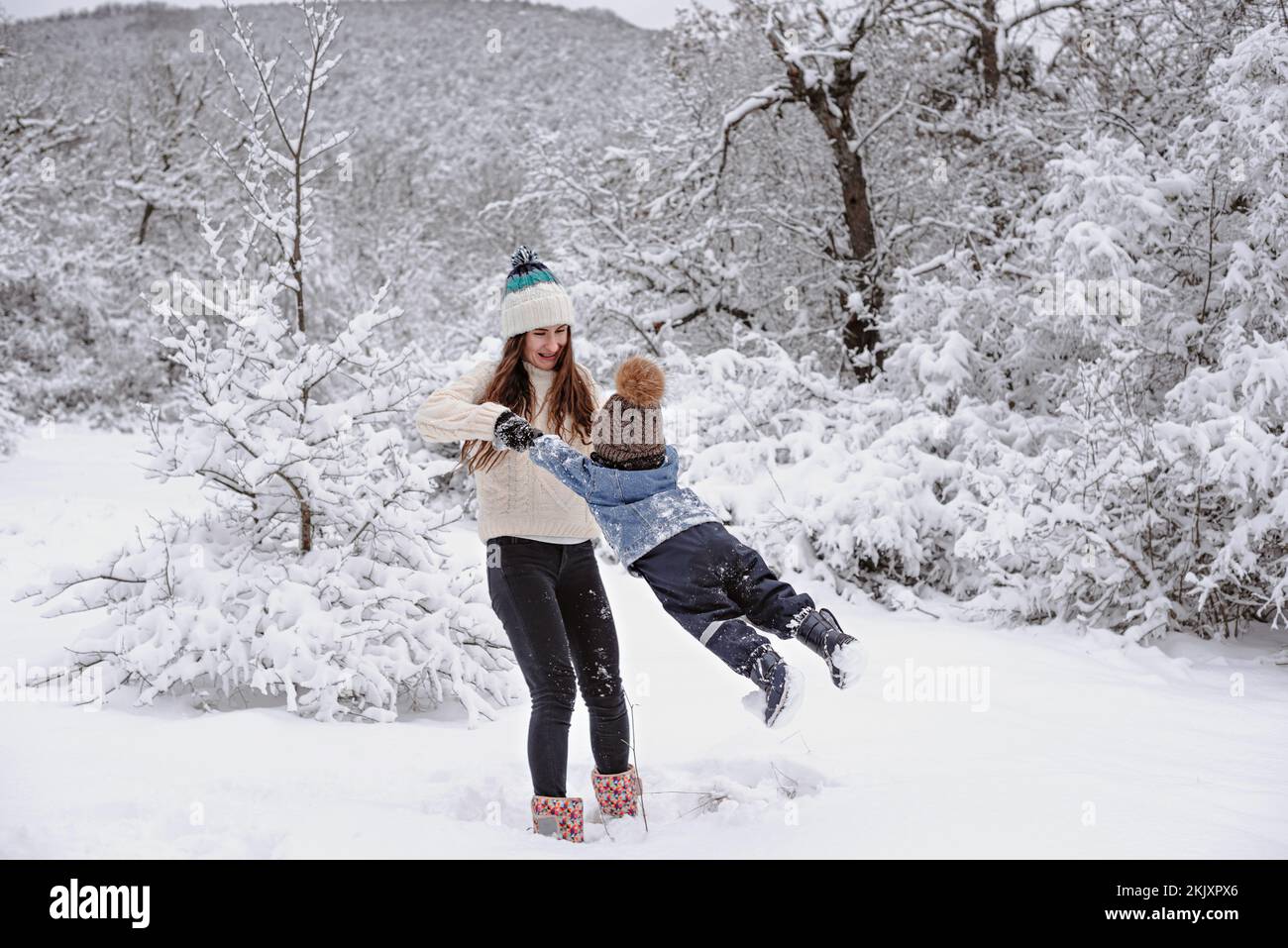 Mom and son are walking in the snow in the winter forest Stock Photo ...