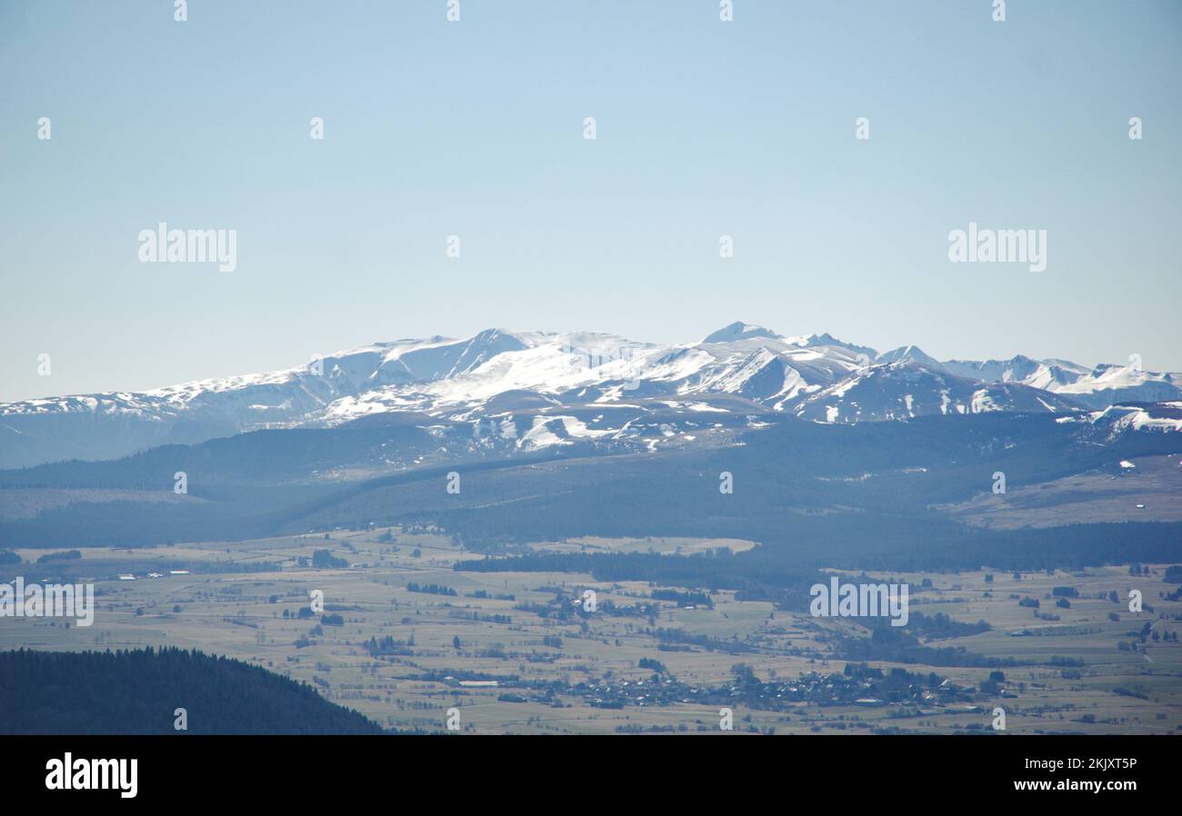 A distant shot of mountain peaks covered with snow surrounded by dense ...