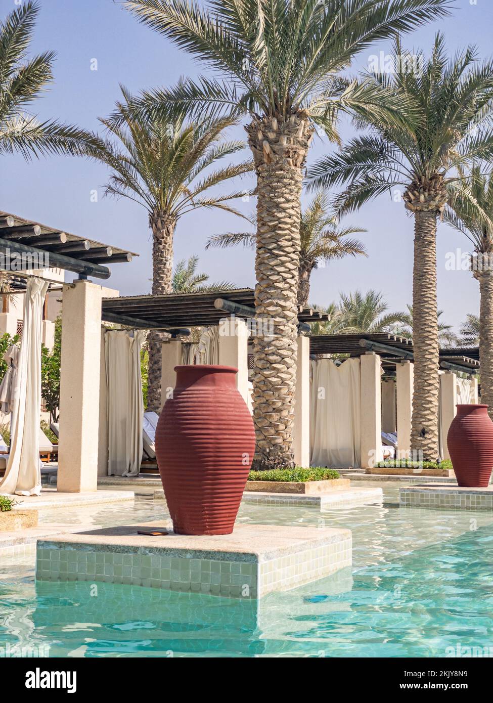 The vast infinity pool with palm trees, large clay pots and cabanas at ...