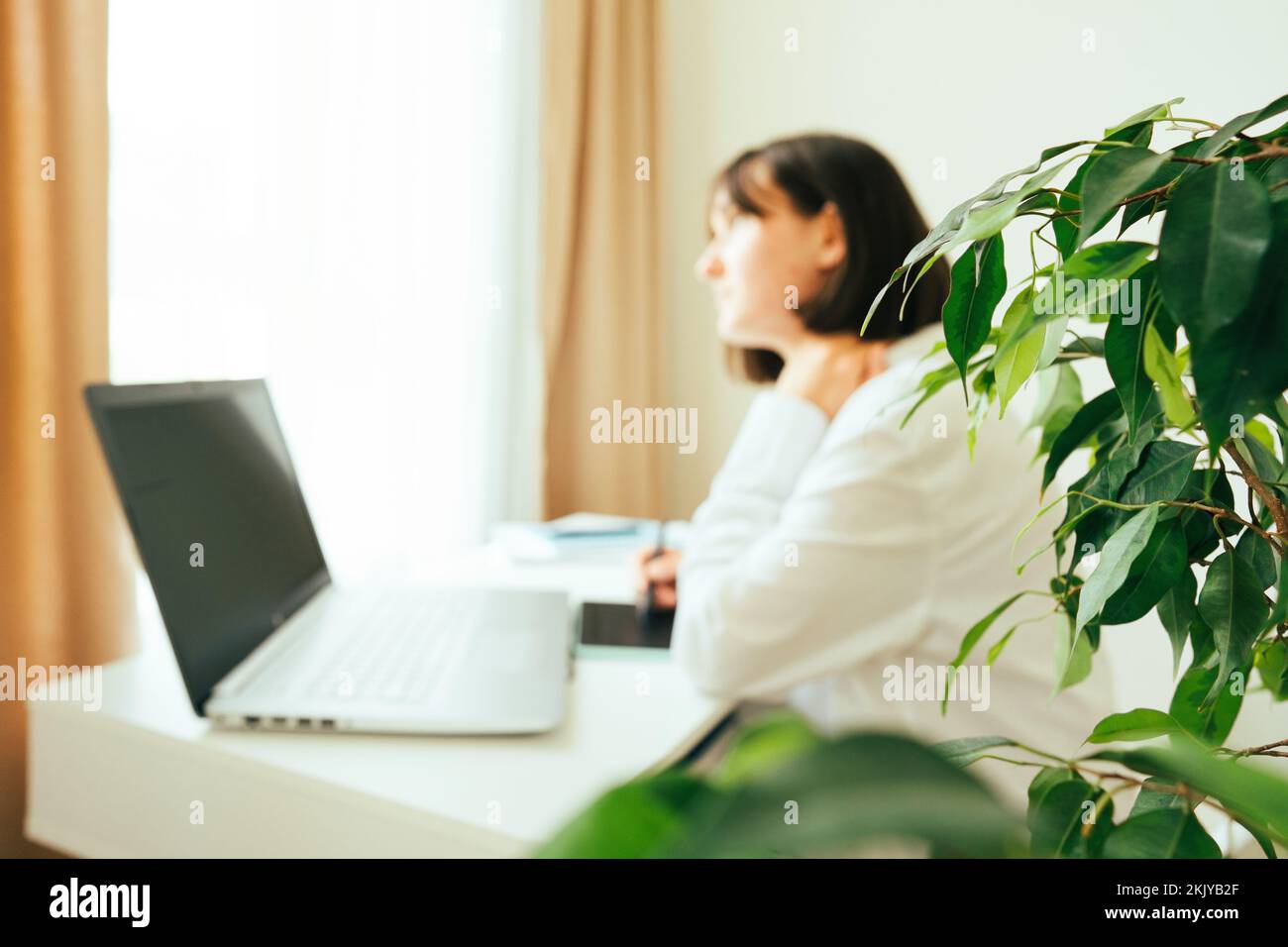 Defocused young woman using laptop computer and graphic tablet in the ...