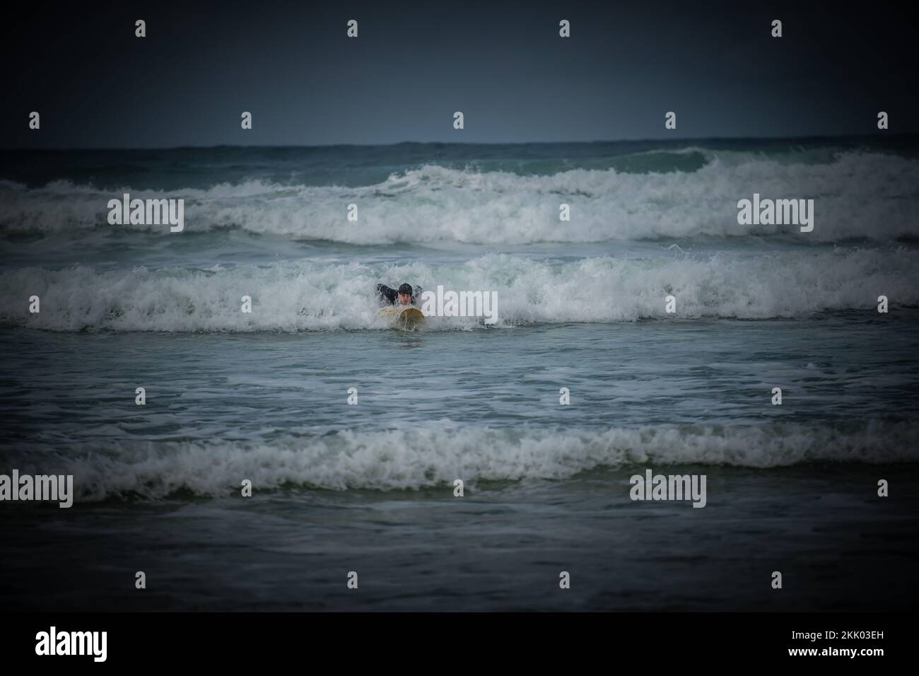 A surfer rides the waves in on the rough seas off the french west ...