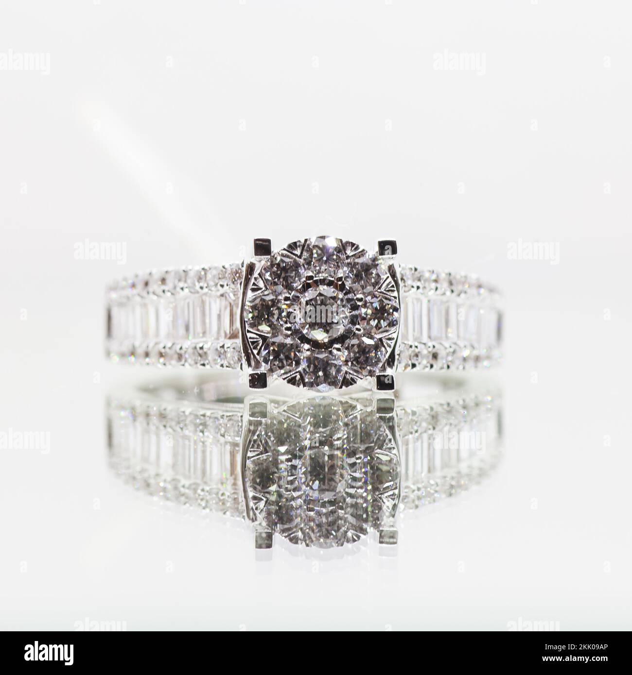 Engagement diamond ring on a mirror surface. emeralds, sapphires, and ...