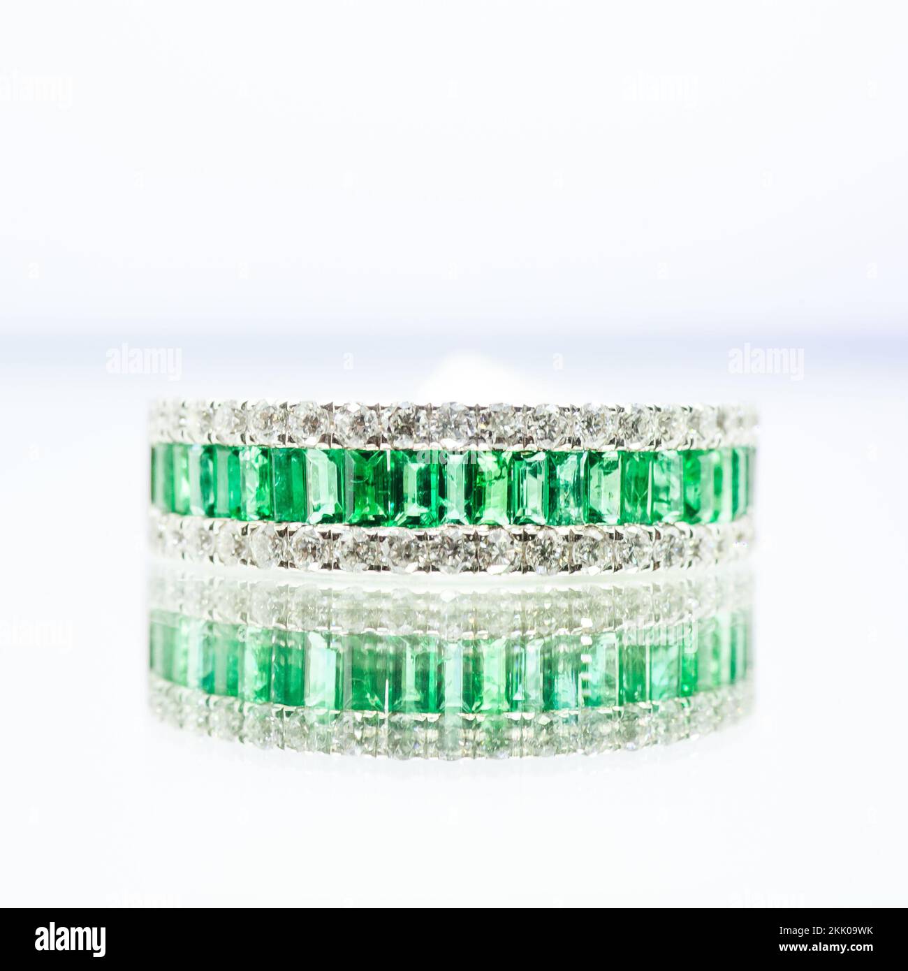 Engagement diamond ring on a mirror surface. emeralds, sapphires, and ...