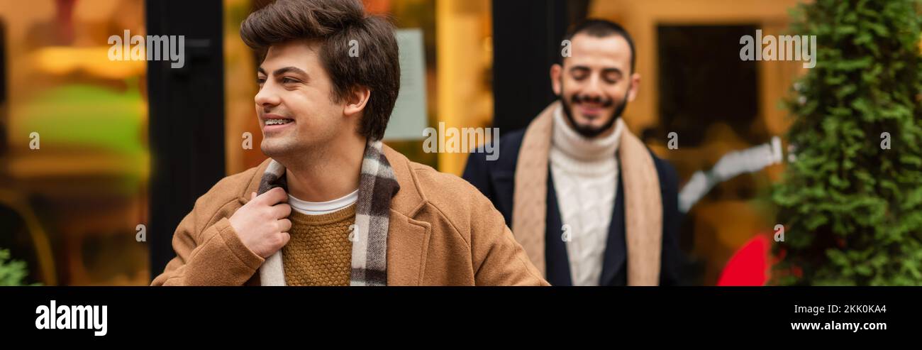happy and stylish gay man looking away near boyfriend on blurred ...