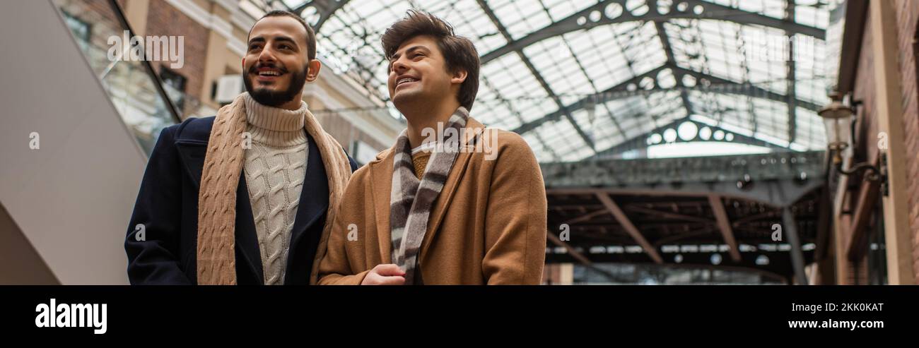 young and fashionable gay men smiling and looking away under ...