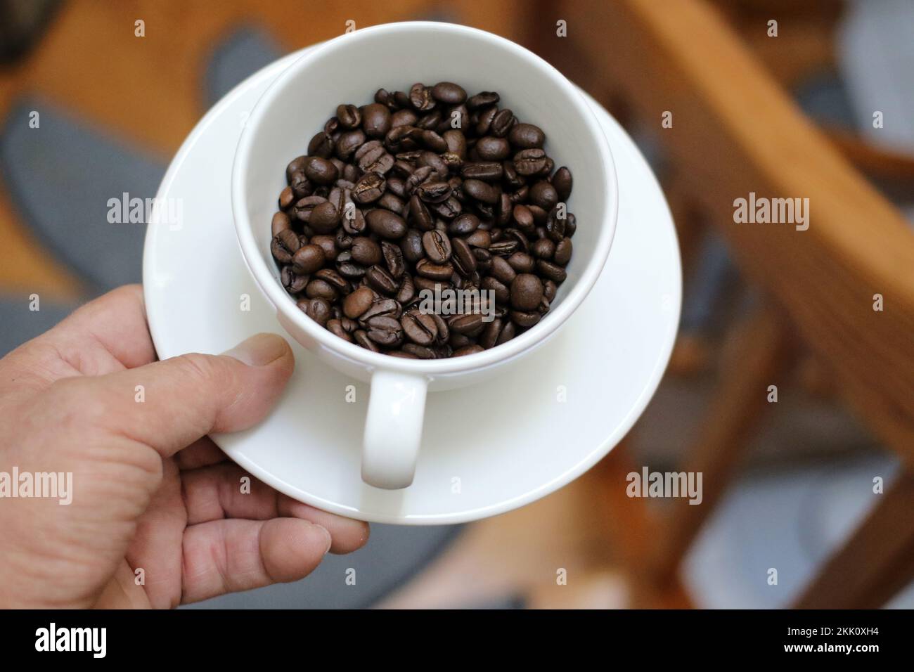 A top view of a white coffee mug filled with coffee beans in the hand ...