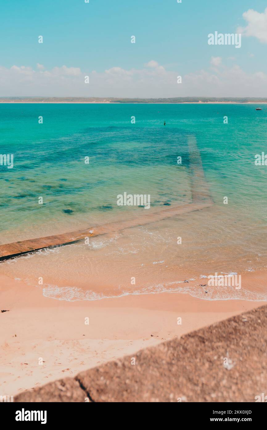 A vertical shot of a sandy beach of an azure sea Stock Photo - Alamy