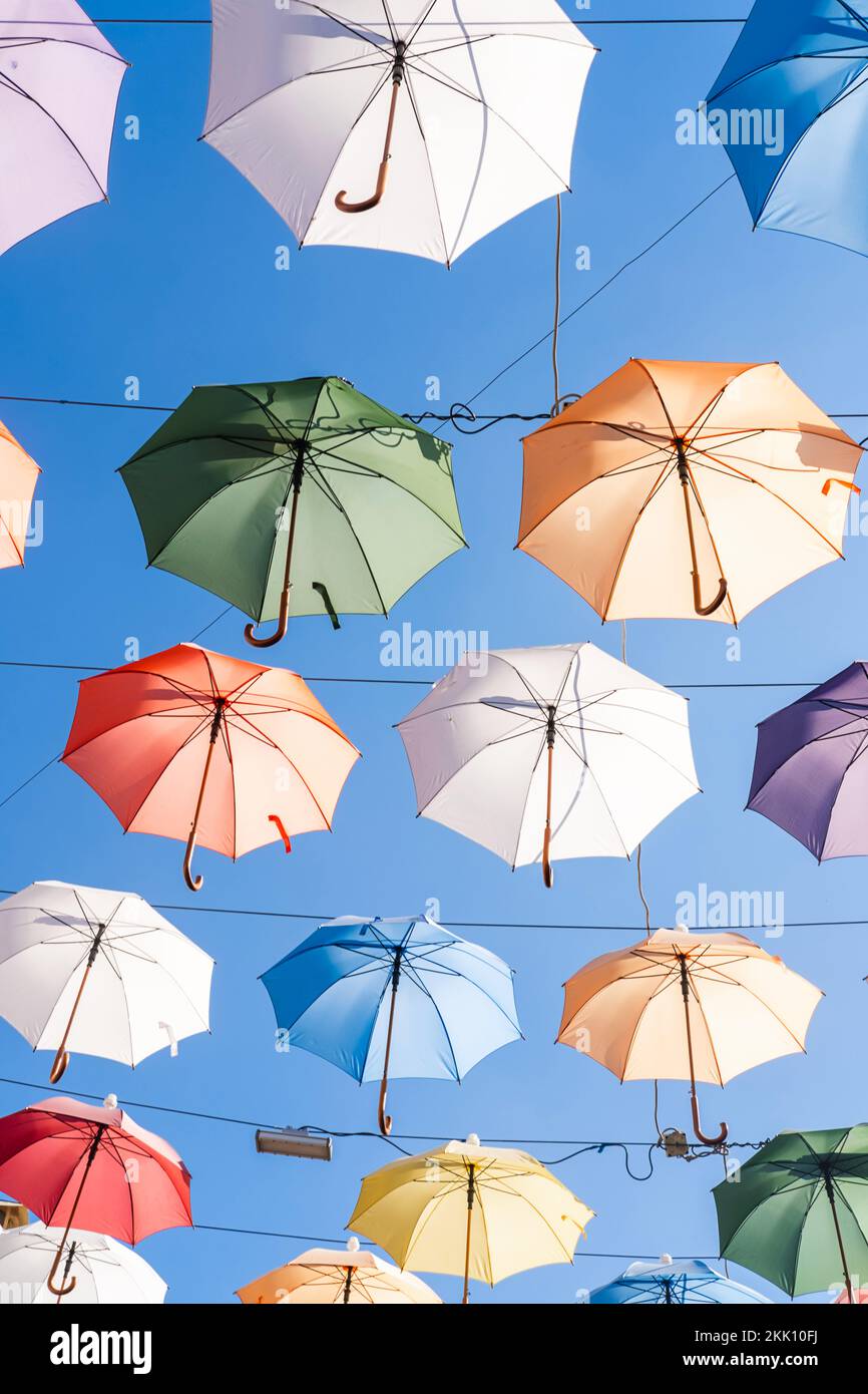 Open multi-colored umbrellas hang over passage between houses Stock ...