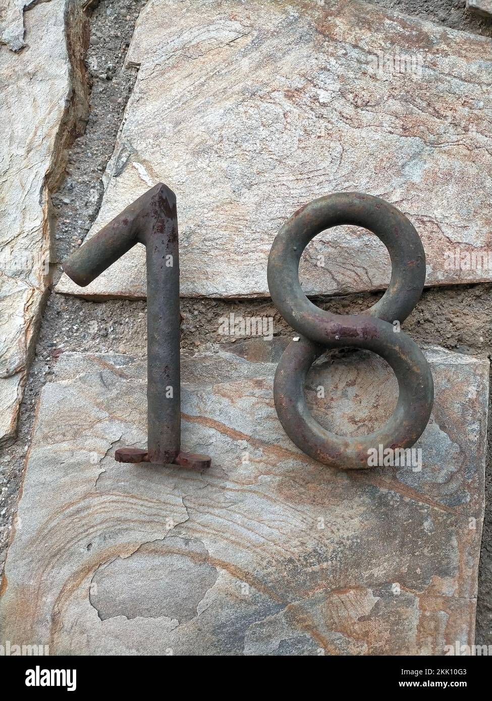 A stone wall with the number 18 on it in rusty iron digits - vertical ...