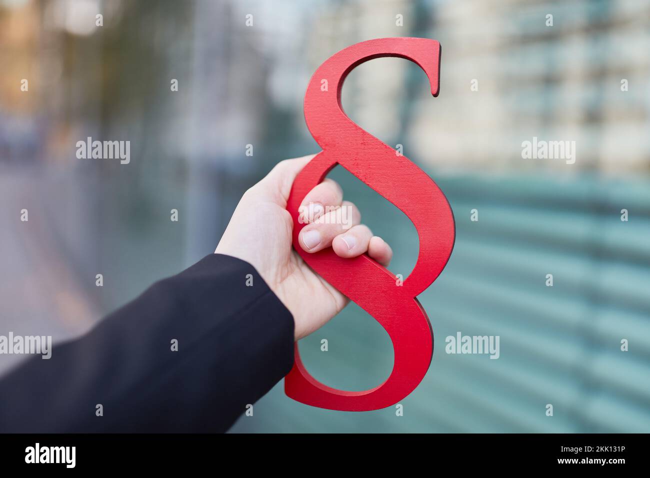 Female hand holding big red paragraph sign as law concept in front of ...