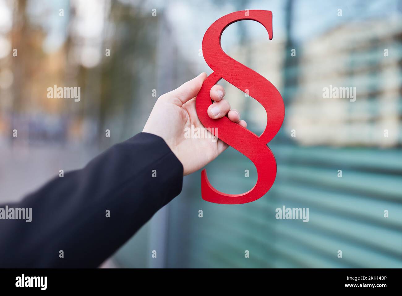 Female lawyer holding big red paragraph sign as law concept in front of office Stock Photo - Alamy