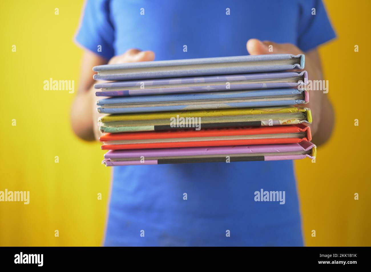 hand holding stack of books on color background Stock Photo - Alamy