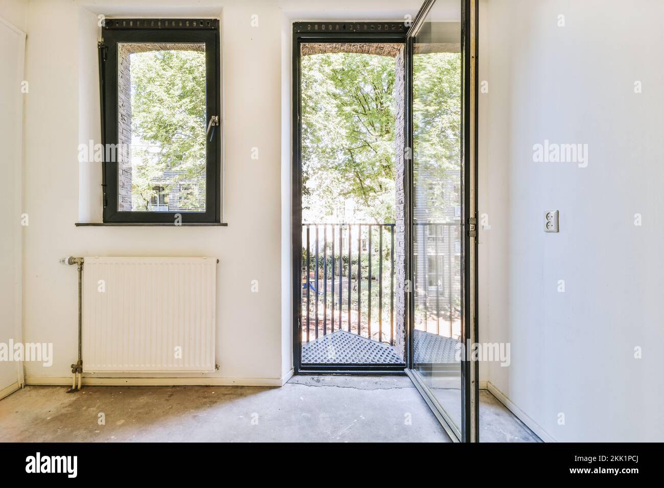 Plastic window and radiator on white wall in empty light room at home ...