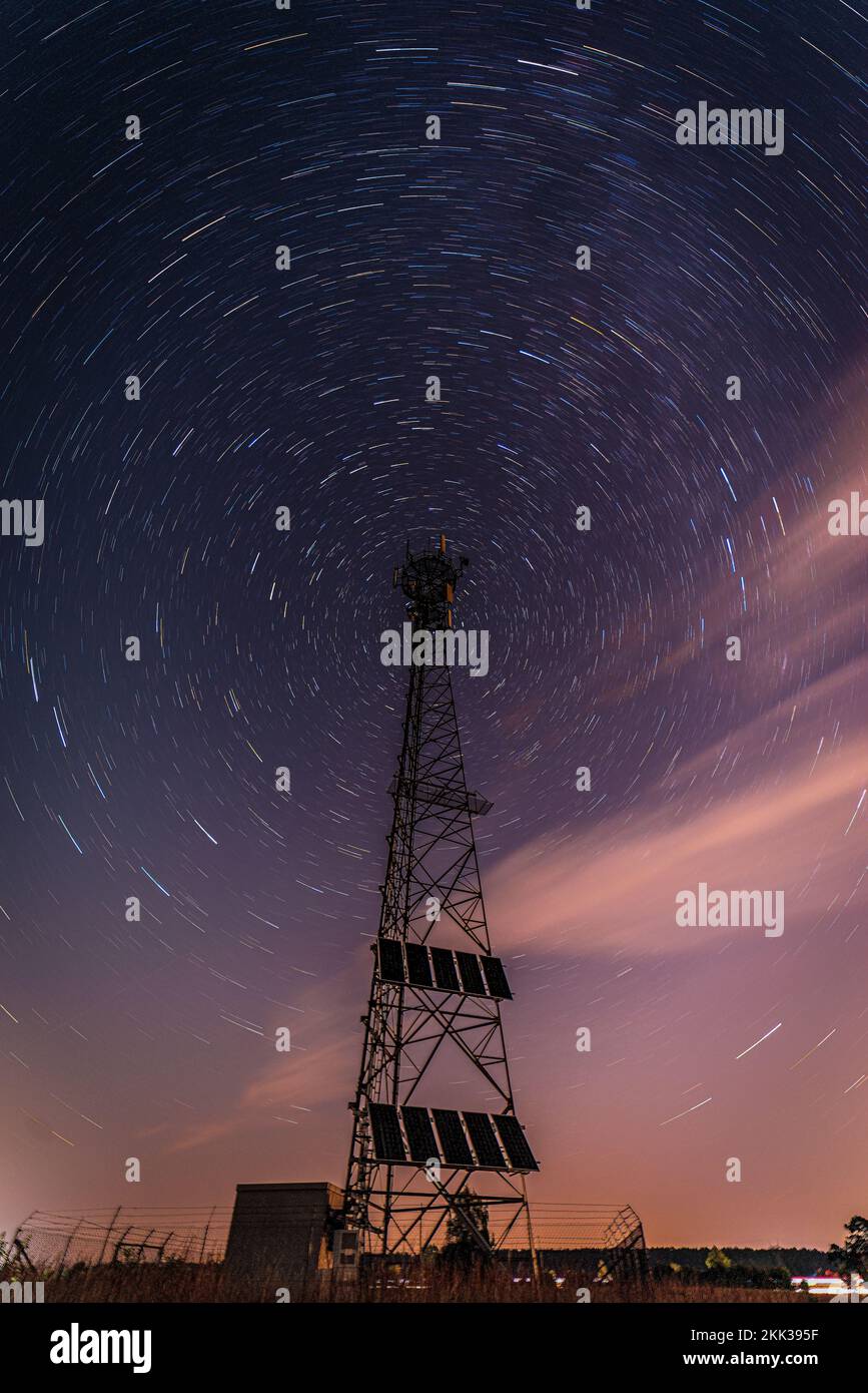 A vertical long exposure of the night stars rounding behind a radio ...