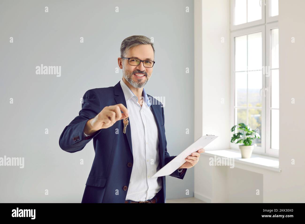 Portrait of friendly male real estate agent showing key to house that ...