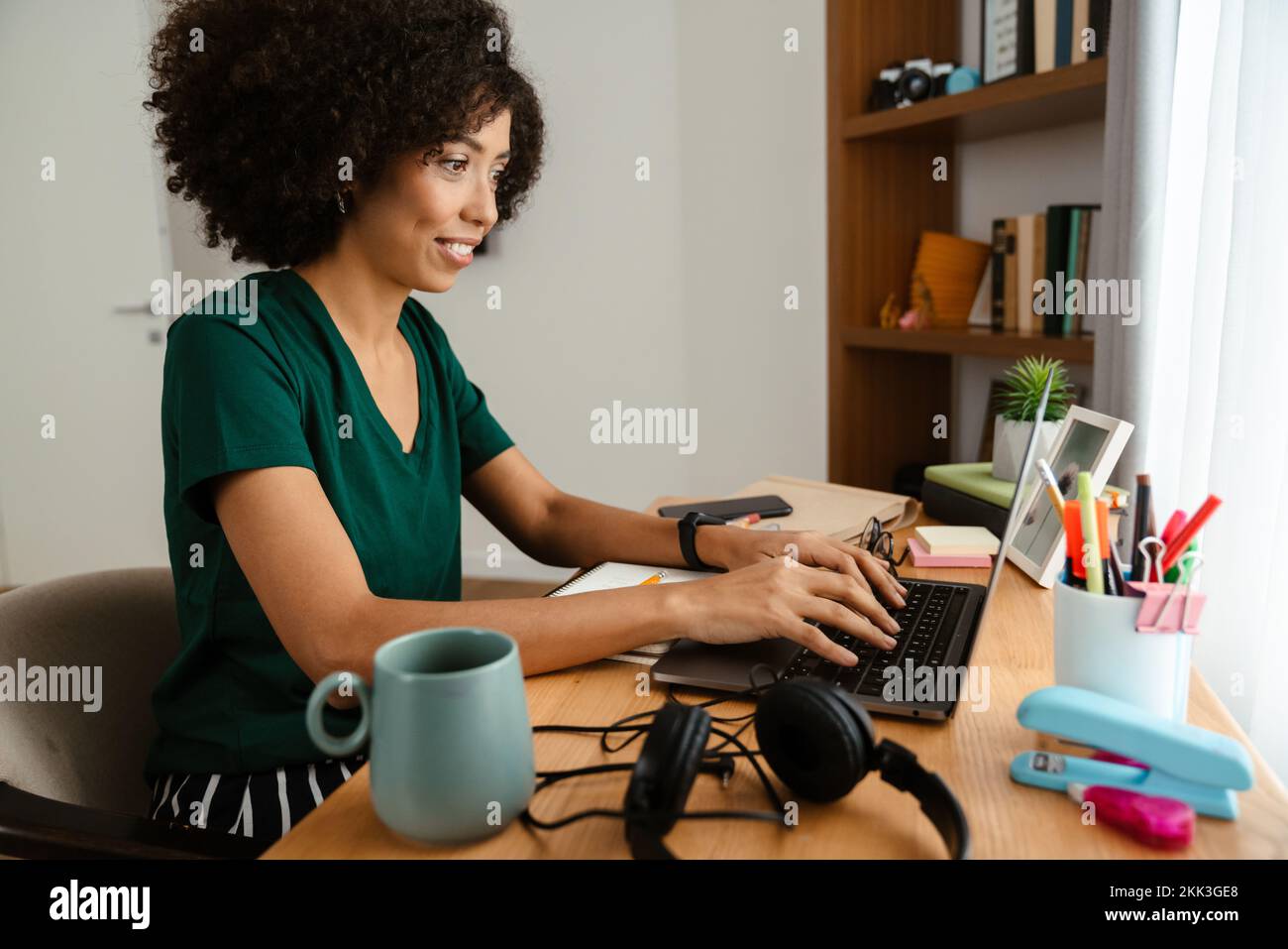 African american young woman with curly afro hairstyle sitting at desk ...