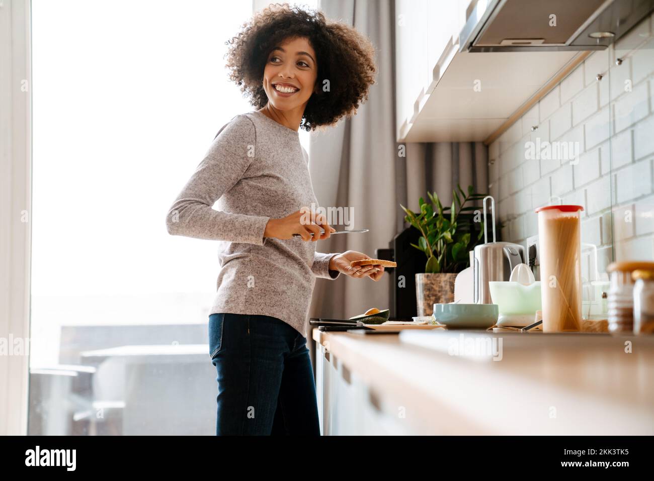 African american young woman with curly afro hairstyle making breakfast ...