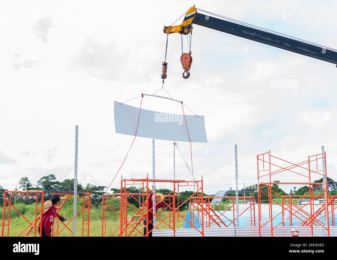 Crain lifting metal sheet silo wall in construction site. Work at ...