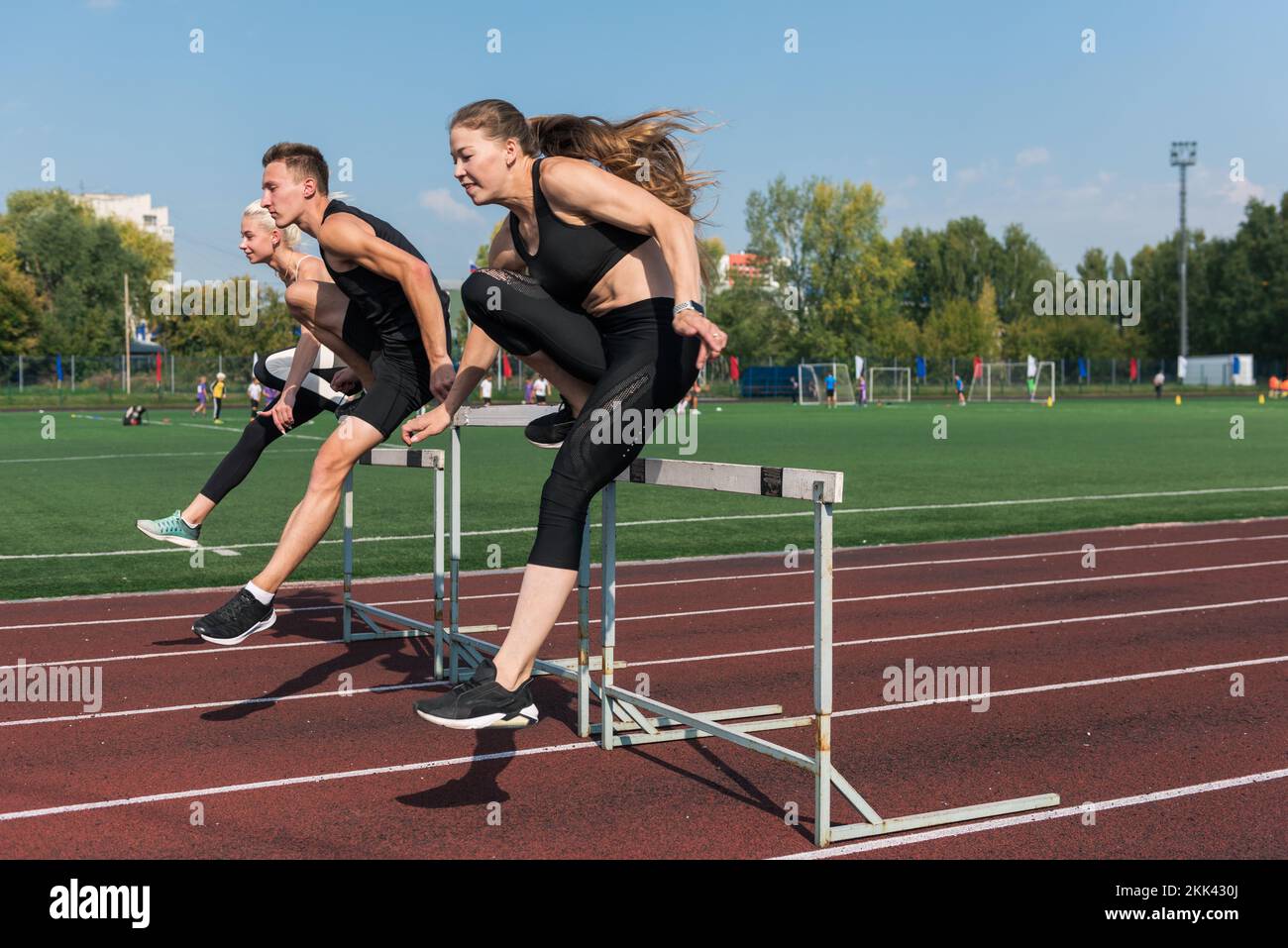 Two athlete woman and man runnner running hurdles at the stadium ...