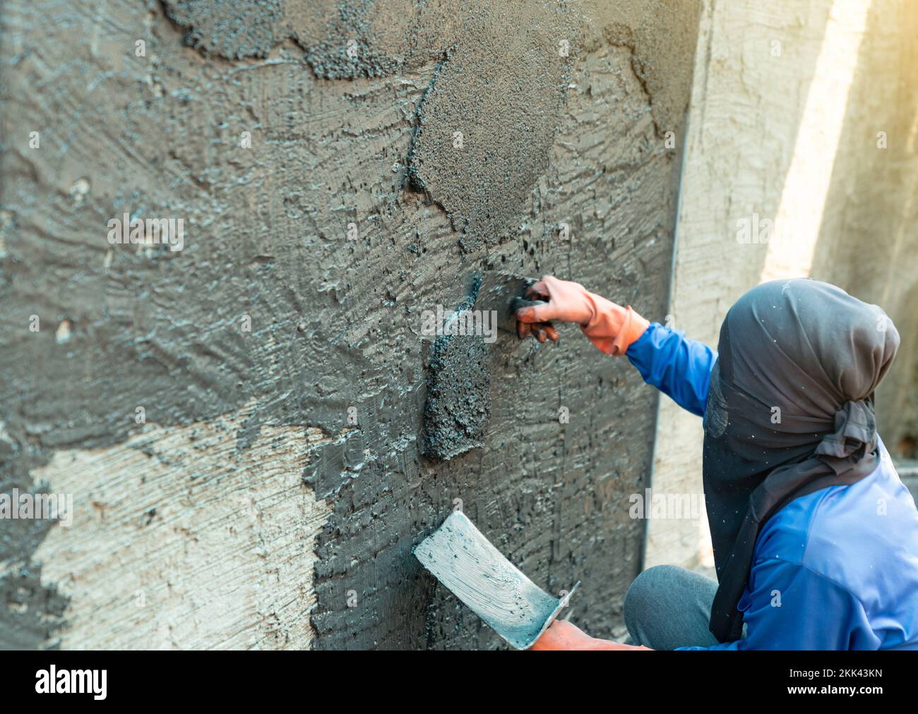 Worker plastering exposed aggregate finish on wall in construction site ...