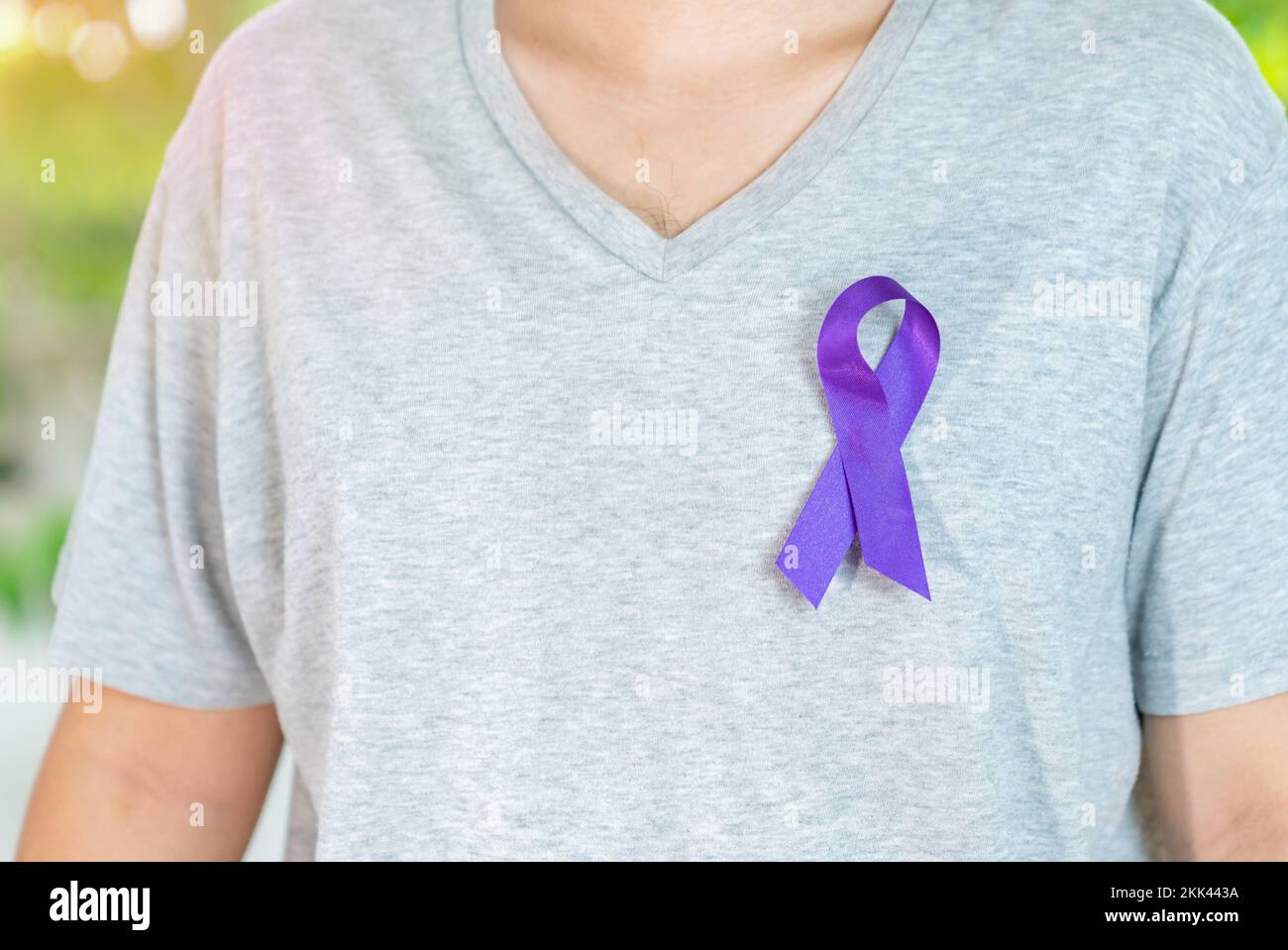 Purple ribbon on chest of the man in grey shirt on out of focus ...