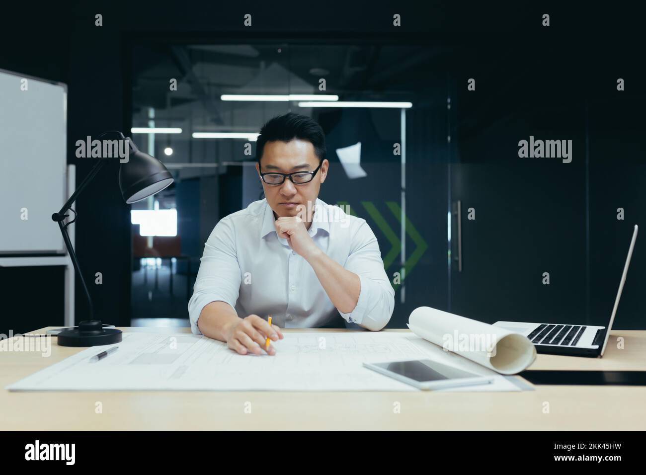 A handsome young man, an Asian architect, designer, engineer, sits at a ...