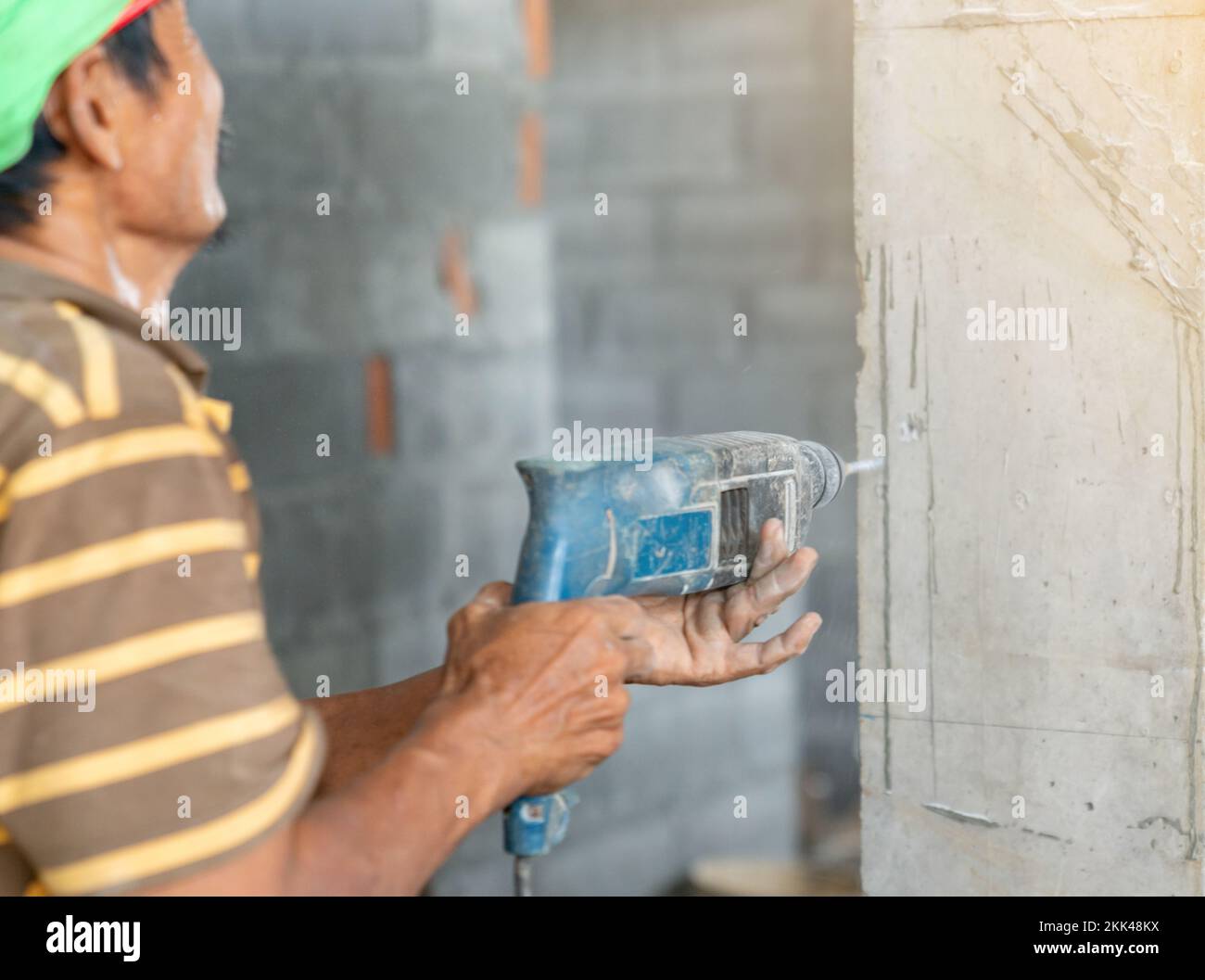 The builder with hammer drill perforator making hole in wall without ...