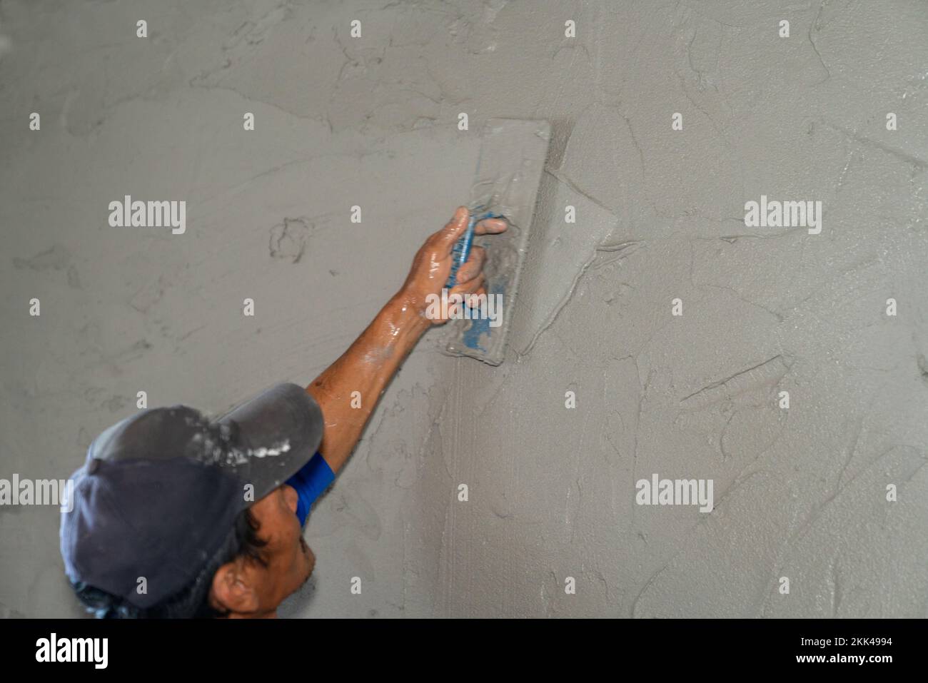 Worker plastering cement on wall for building house in construction ...