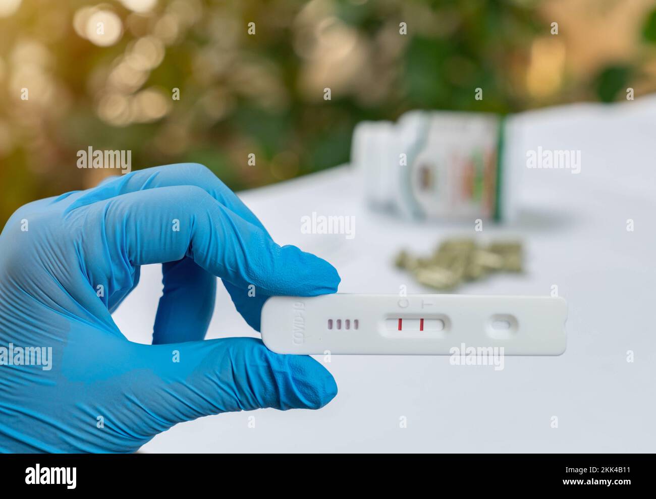 Hand with gloves holding a Positive Covid-19 Rapid Antigen Test Result ...