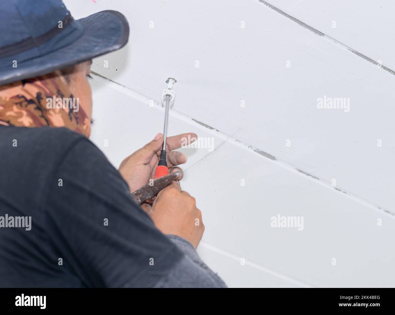 Technician install clamp for pipes on the ceiling using a screwdriver ...