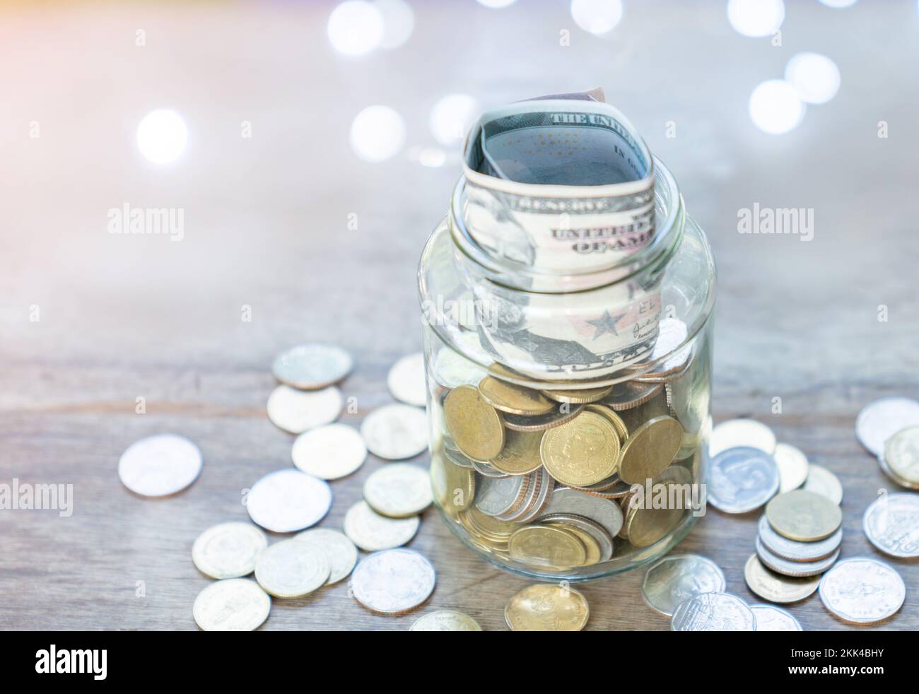 A clear glass jar filled with cash and coins on bokeh background Stock ...