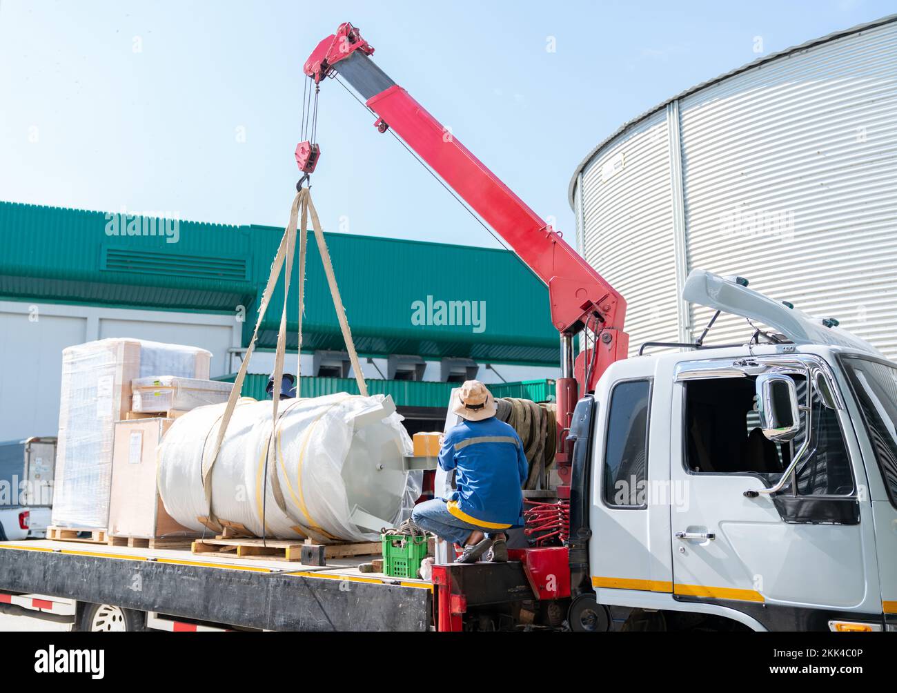 Worker use crain lift up air compressor tank from truck put down on the ...
